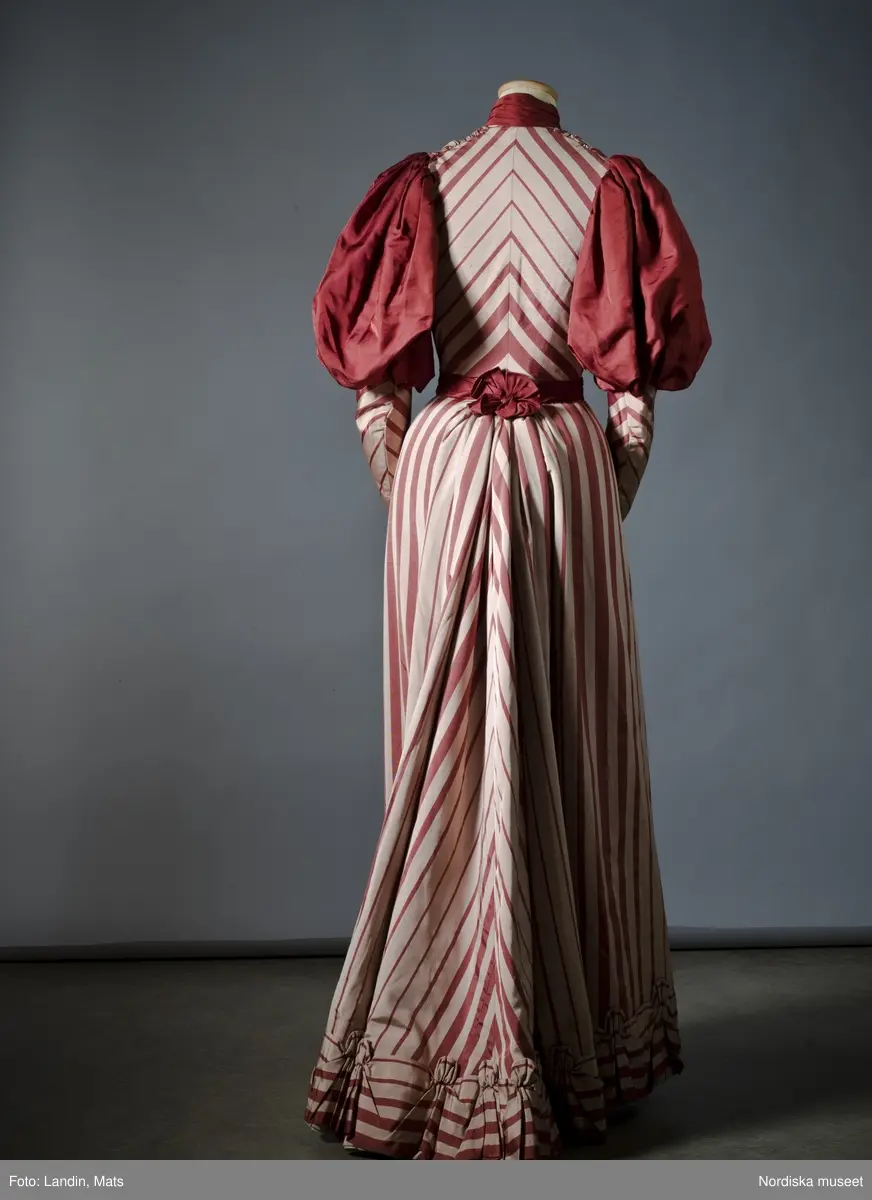 Klänning av ripssiden, röd- och beigerandig med vinröda puffärmar. 1890 ...