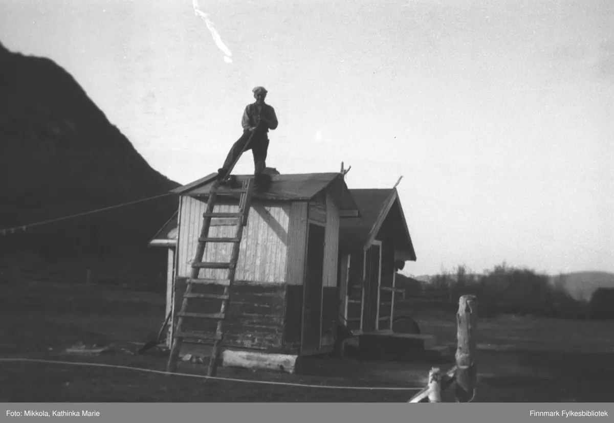 Leif Mikkola arbeider på taket til et lite uthus på Mikkelsnes ...