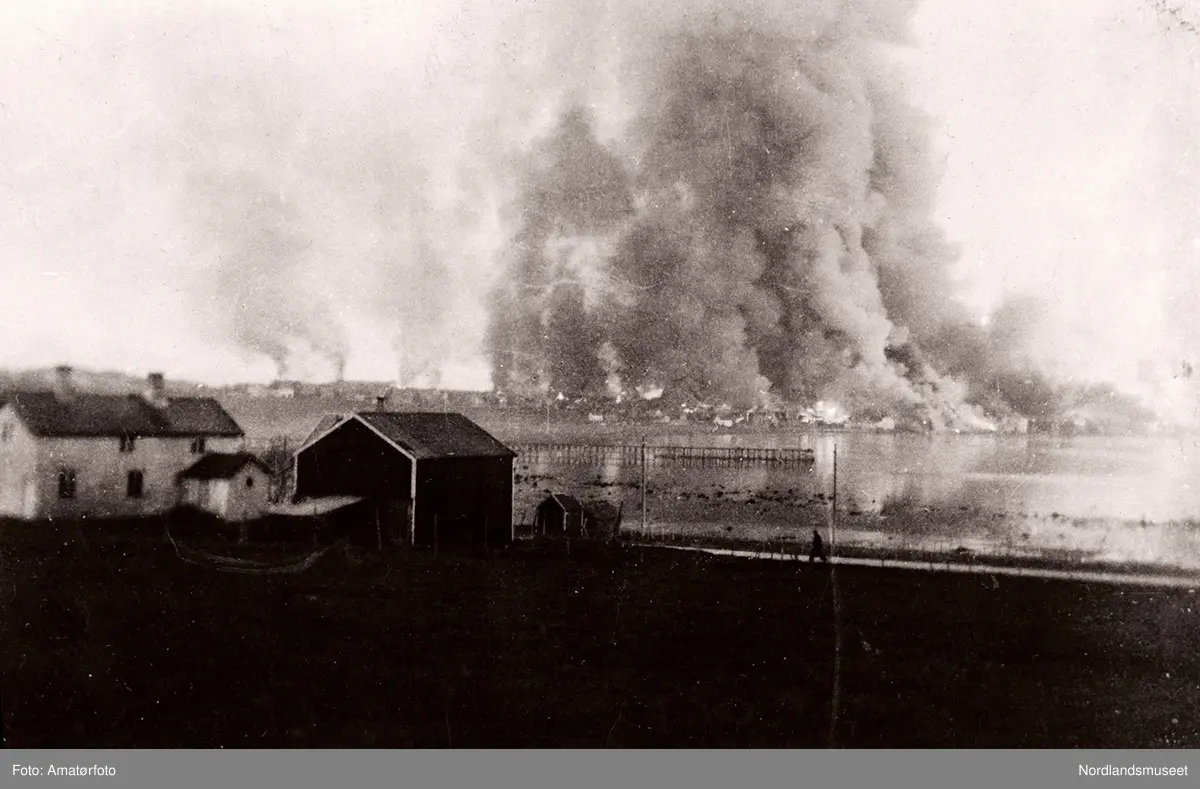 Bodø by brenner etter bombingen 27.5.1940. Tatt fra Rønvika. Dyrka mark ...