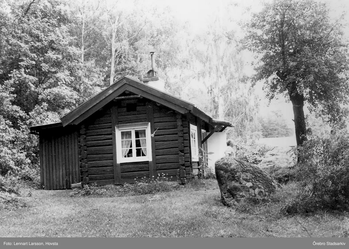 Greta Olsson bakom en sten vid stuga i Yxta i Hovsta, 1984 - Örebro ...