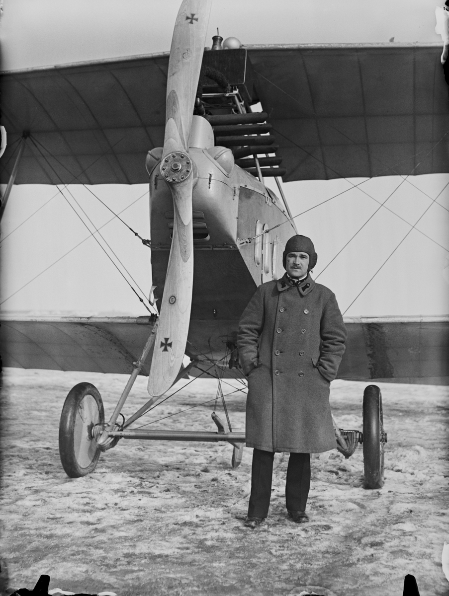 Porträttfoto av en flygare i flygarhuva vid nosen på ett militärt ...