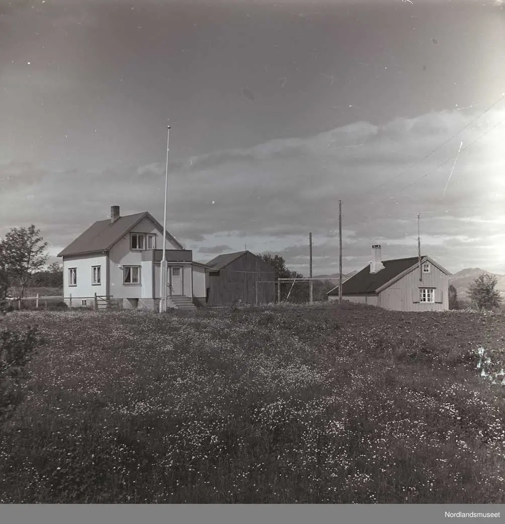 Husmannsstue. Hvitt hus med bislag, trappe og balkon, en flaggstang ...