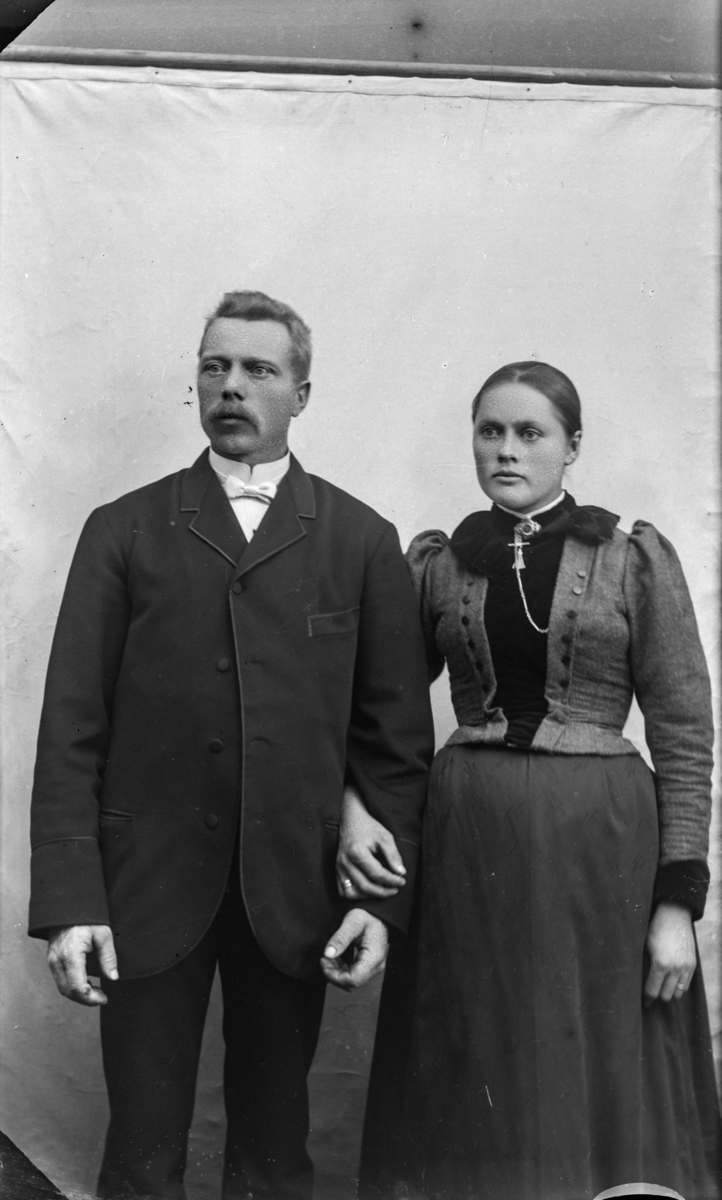 Ektepar med kvinne med glatt hår med midtskille, kledd i mørk stakk og ...