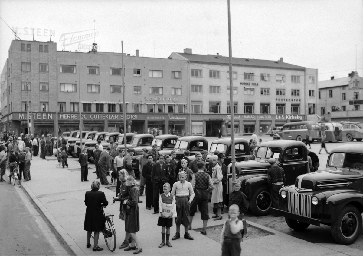 Østre Torg, Hamar. Lang rekke med Ford V8 lastebiler. Avisselger ...