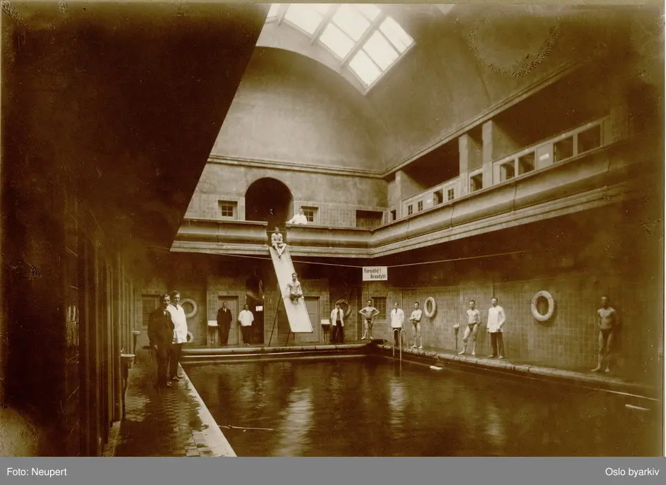 Bislett bad. Basseng med sklie. Badende og ansatte langs bassengkanten ...